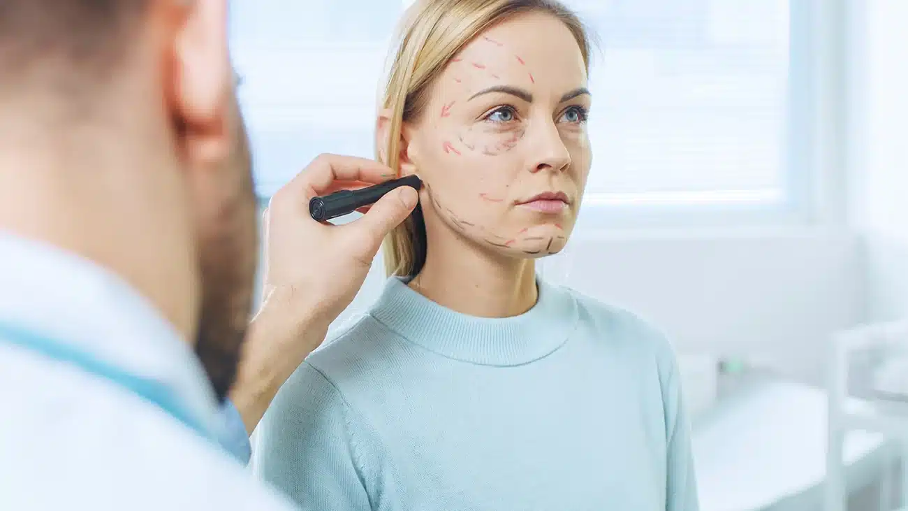 Surgeon using a surgical marker to map out a patient's face for a ...